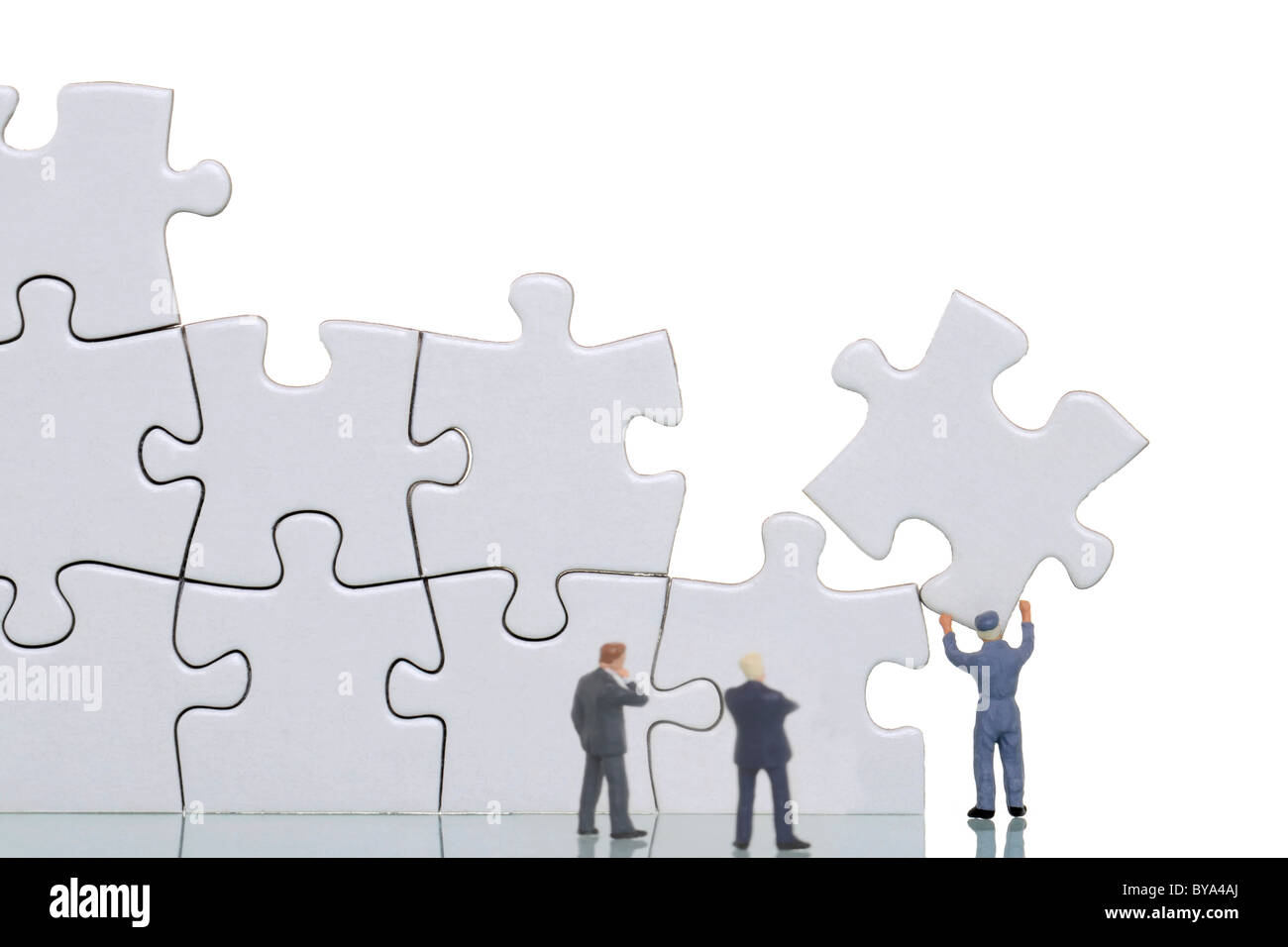 Worker figure building a white jigsaw puzzle, two managers figures ...