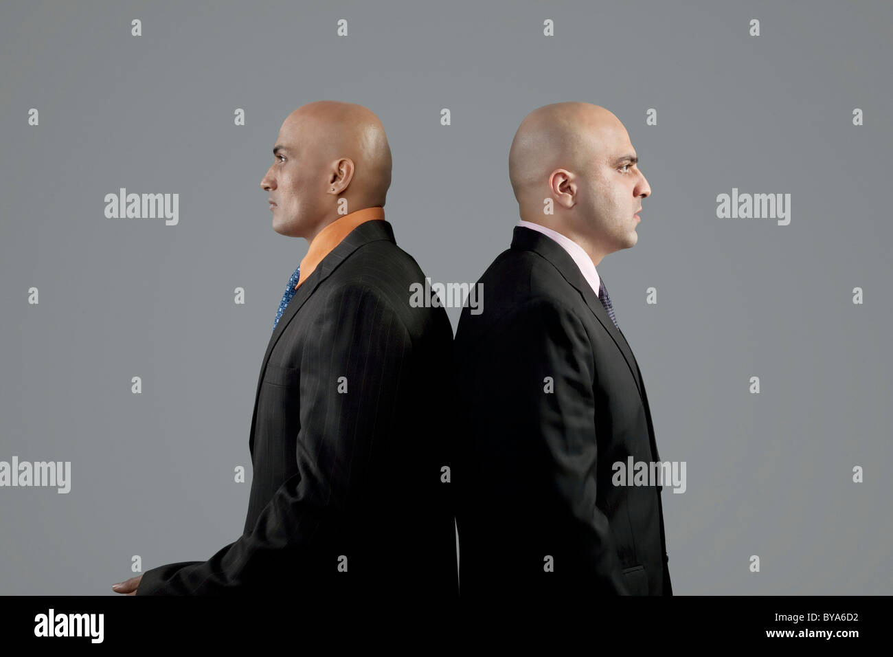 Two bald businessmen standing back to back Stock Photo - Alamy