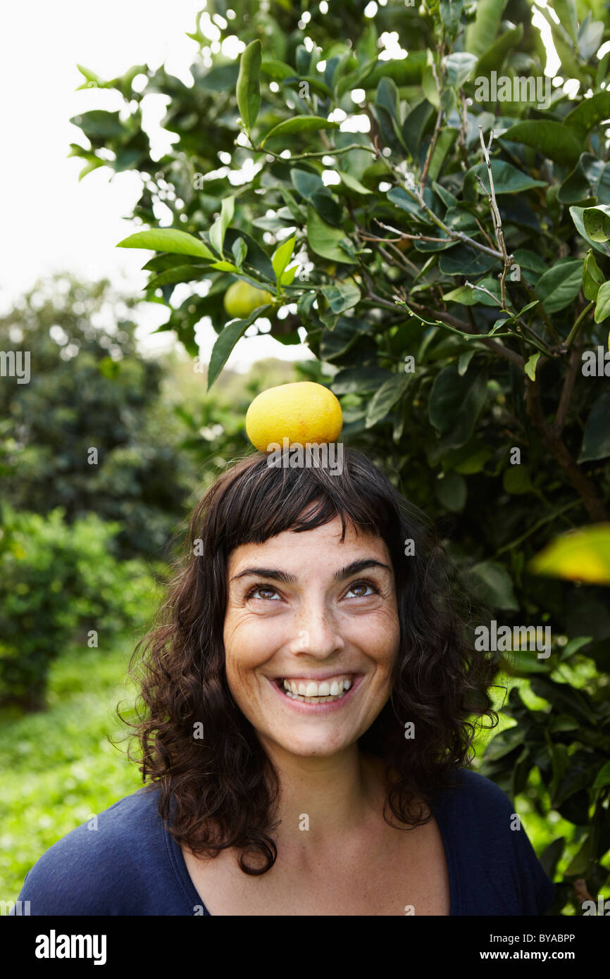 Woman balancing mandarin on her head Stock Photo - Alamy
