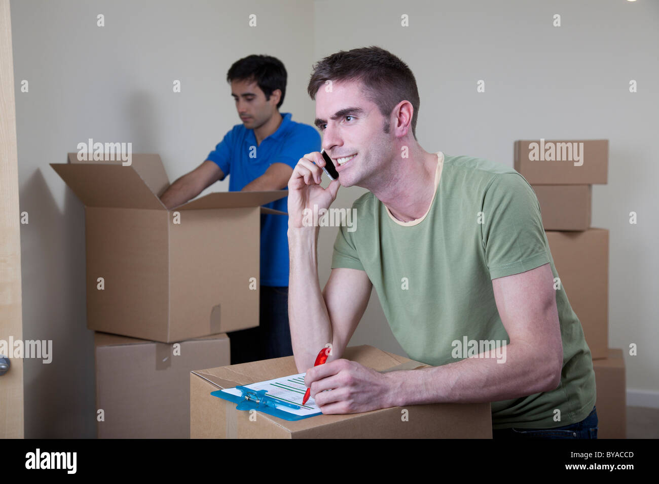 Two men unpacking boxes in apartment Stock Photo - Alamy