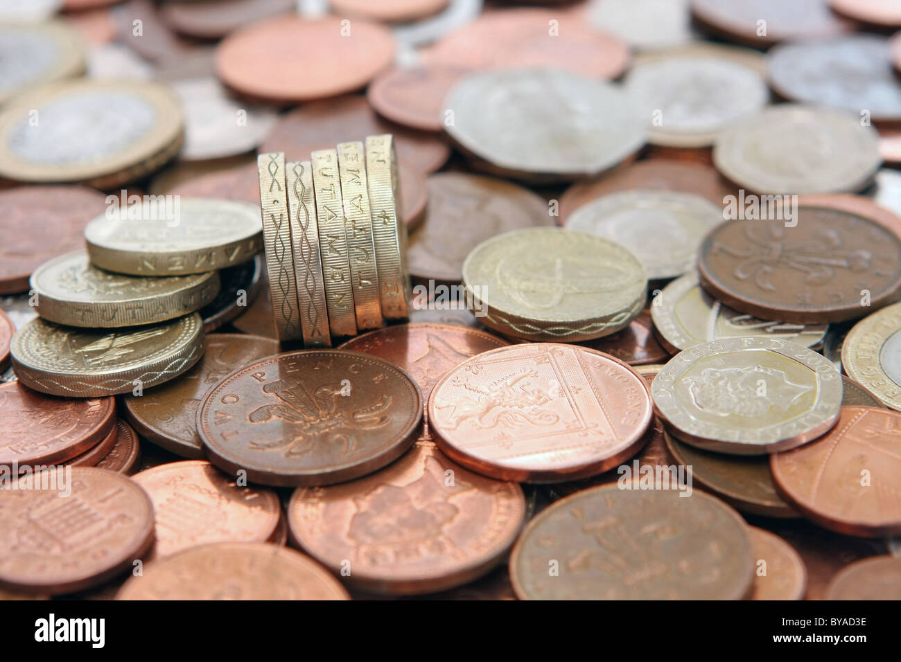 A small row of sterling £1 coins on a jumble of mixed sterling coins ...