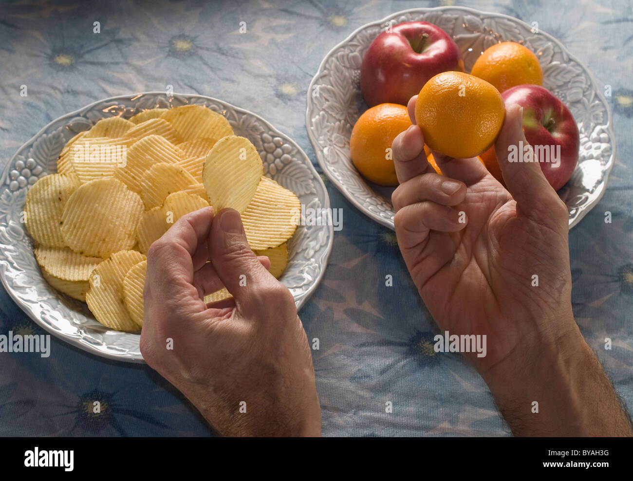 man comparing a potato chip and an orange Stock Photo - Alamy