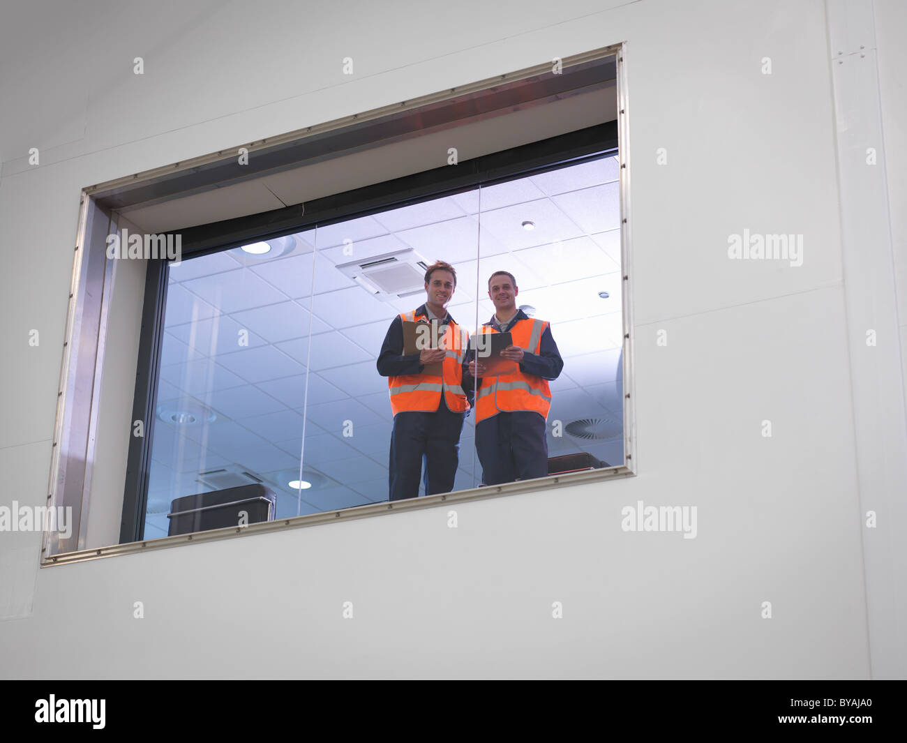 Engineers look out of window in hangar Stock Photo - Alamy