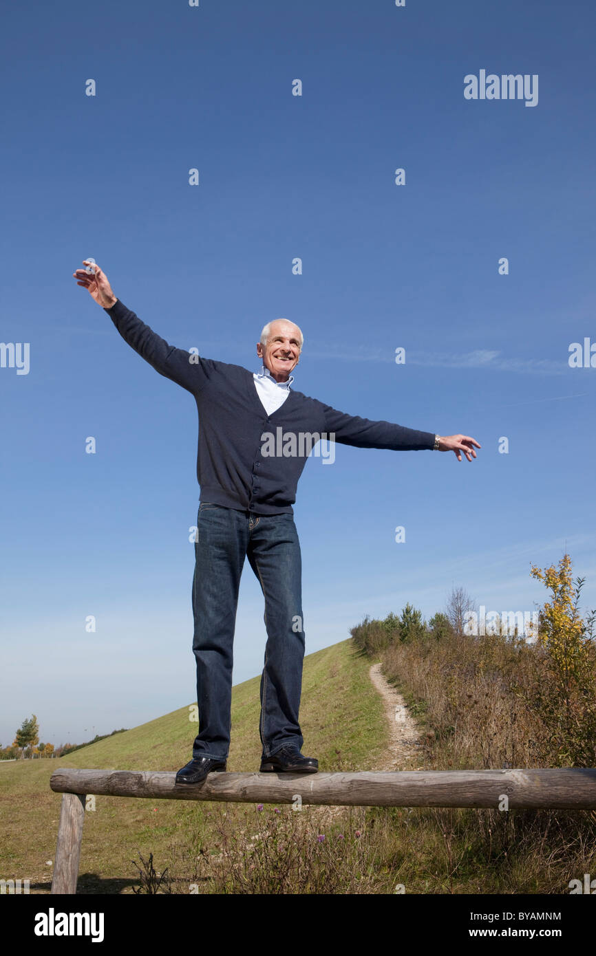 Senior man balancing along a wooden log Stock Photo - Alamy