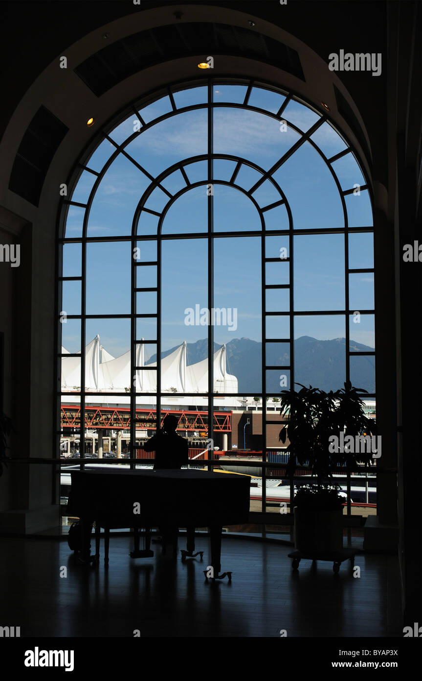 Looking out of an arched window of a shopping arcade onto Canada place ...