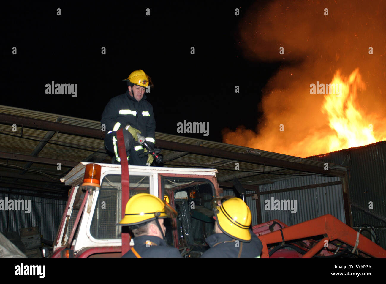 Firefighter using a tractor as a firefighting platform Stock Photo - Alamy