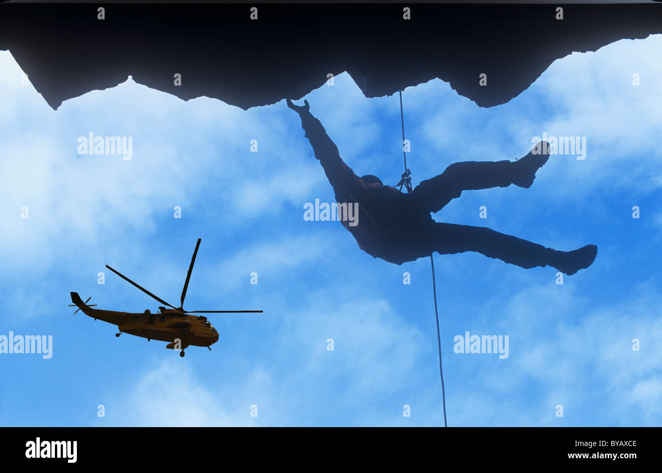 A man abseiling down a cliff in the Lake District, UK, with a ...