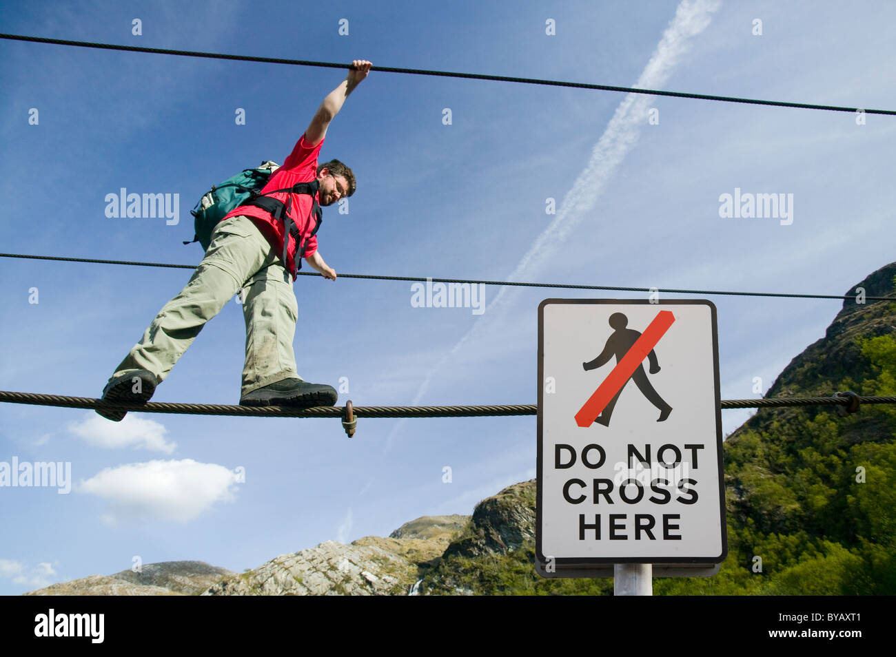 a climber crosses the rope bridge in glen Nevis at Steall Falls Stock ...