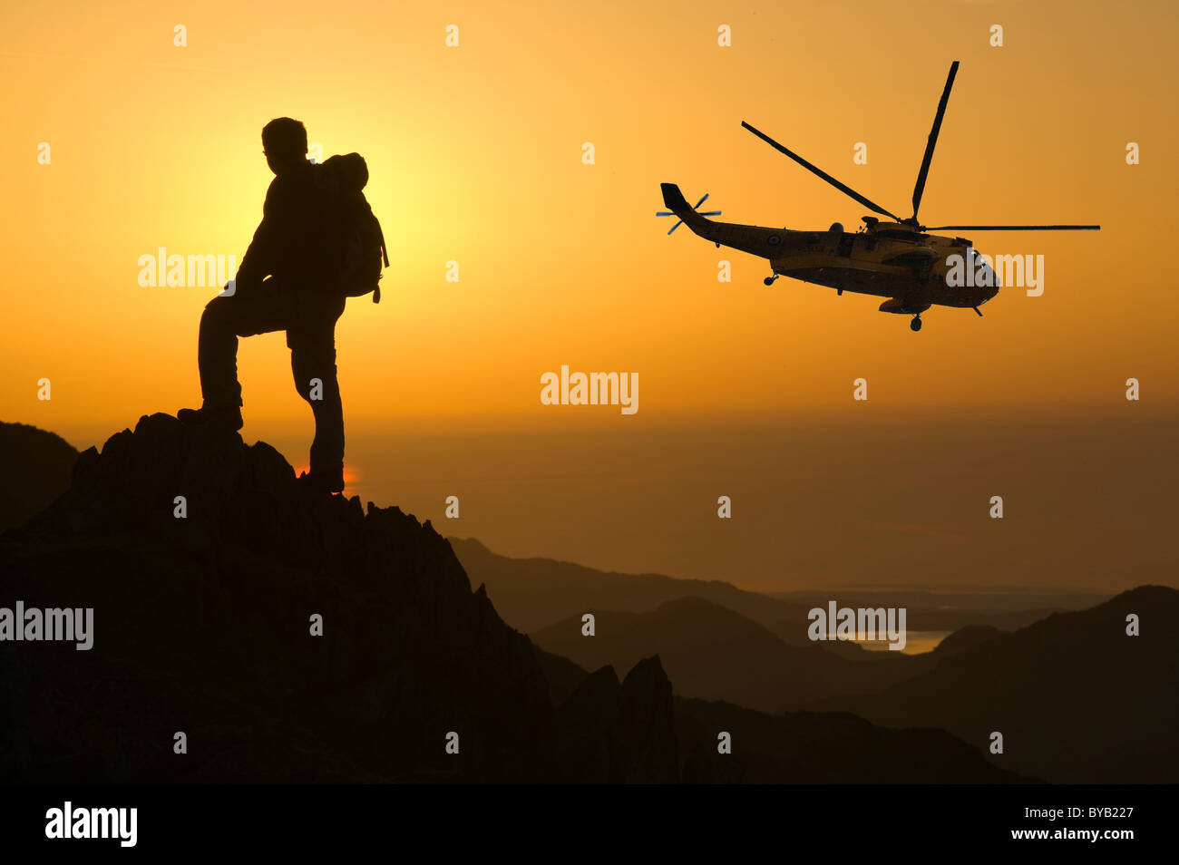 A walker on Swirl Howe Lake District at sunset UK, with a Sea King ...