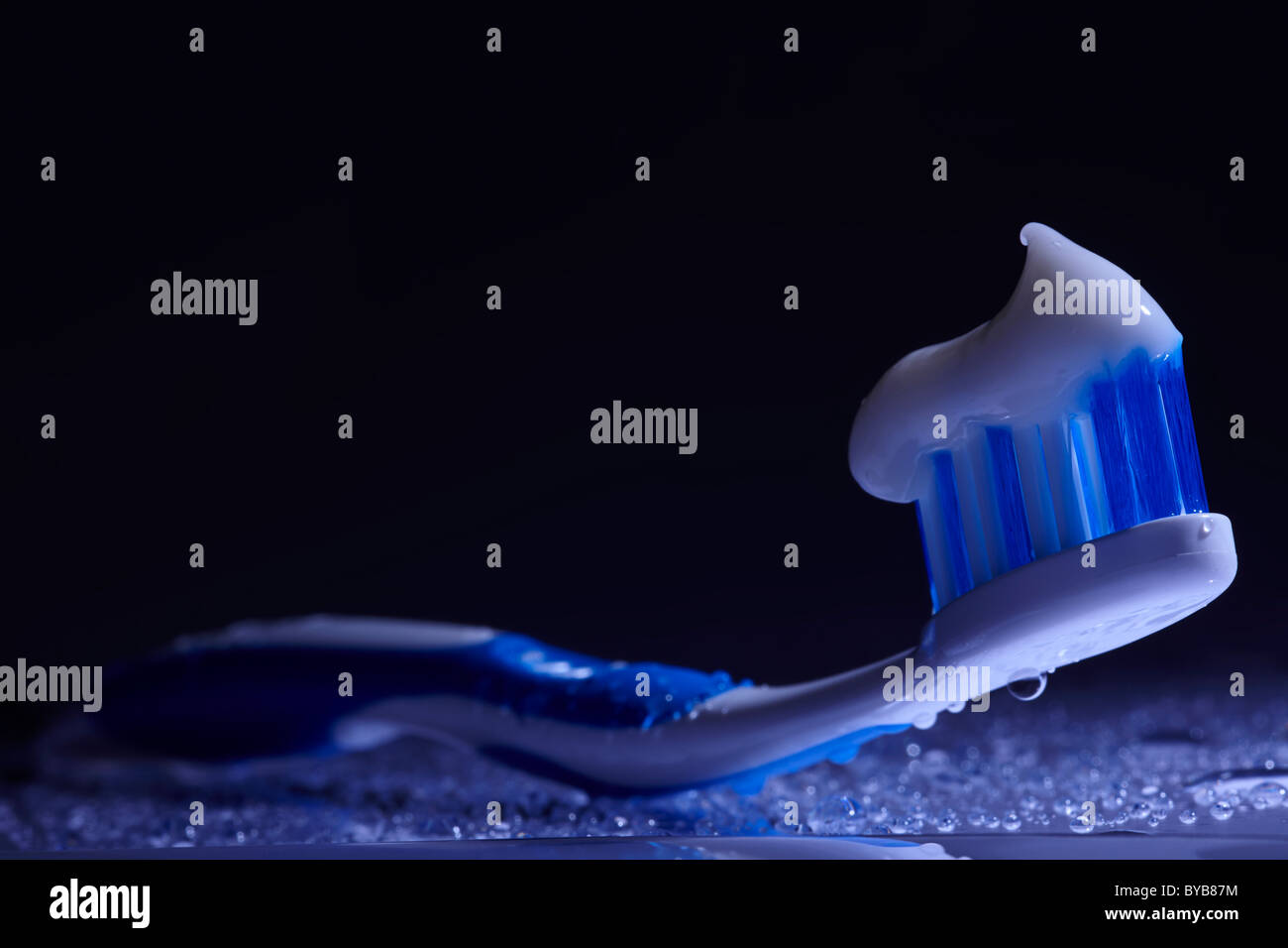 Blue and white toothbrush with toothpaste surrounded by water and water ...