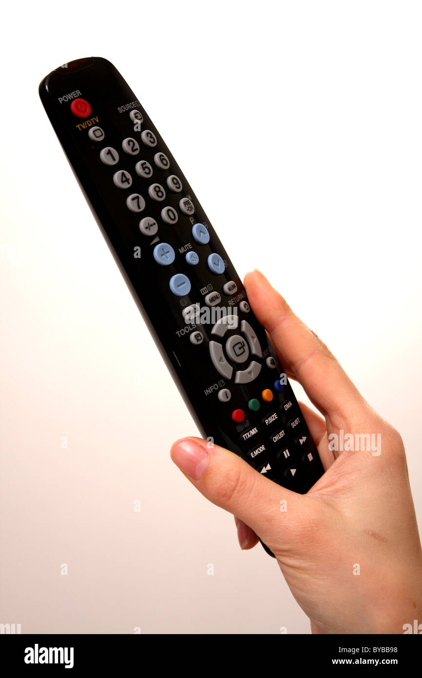A black remote control for a TV held by a Caucasian female on a white ...