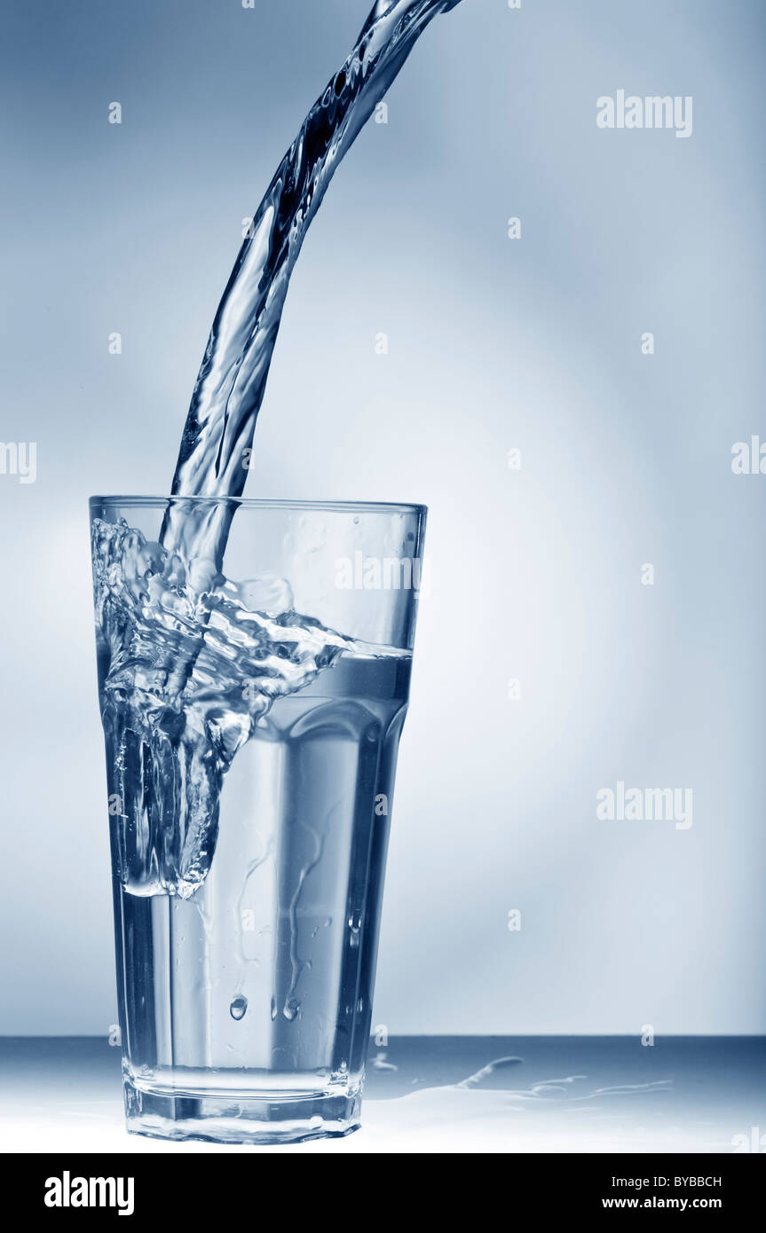 Fresh water pouring into glass over gradient background Stock Photo - Alamy