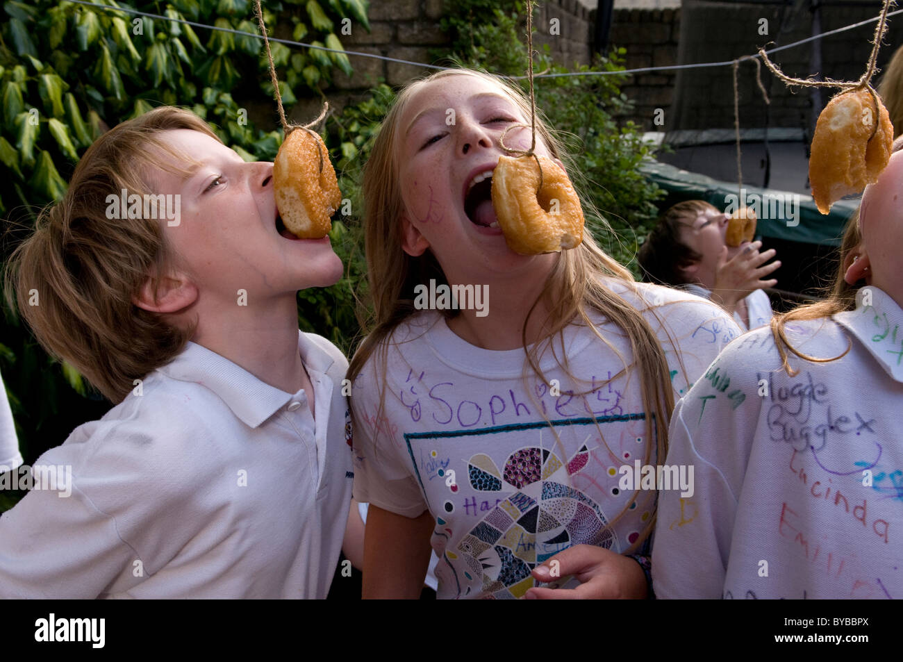 Children eating doughnuts off a string Stock Photo - Alamy