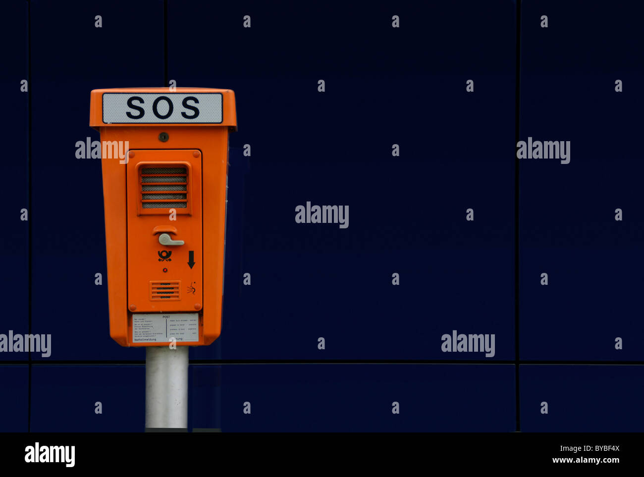 Orange emergency telephone in front of a blue wall Stock Photo - Alamy