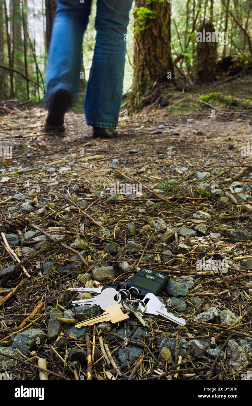 A set of house and car keys lay on the forest floor as a person walks ...