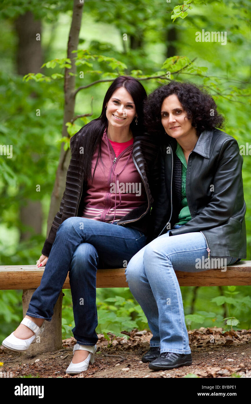 Portrait of two beautiful ladies sitting on a bench in park Stock Photo ...