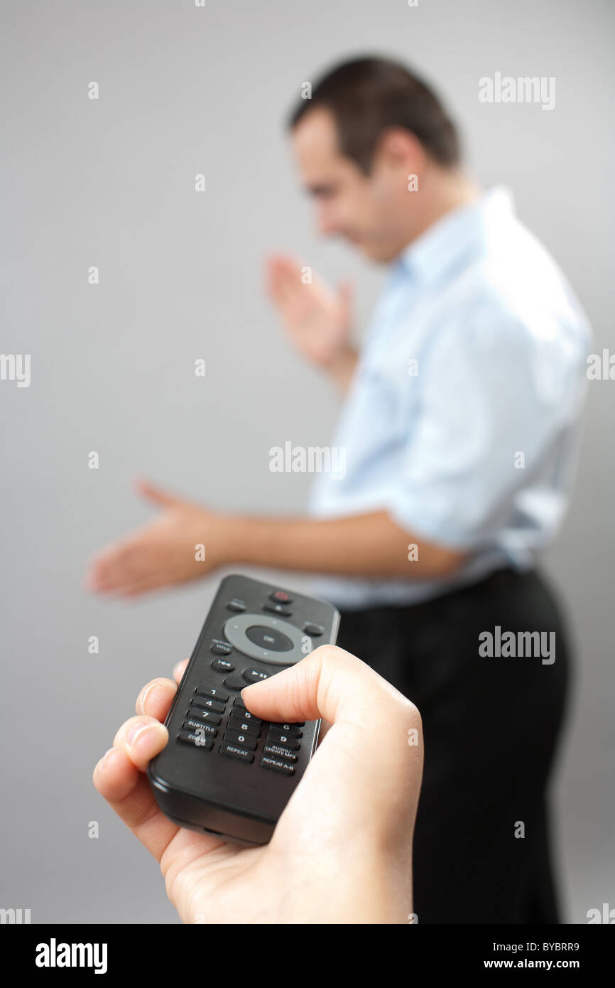 Conceptual shot of a man being controlled by his wife with a remote ...