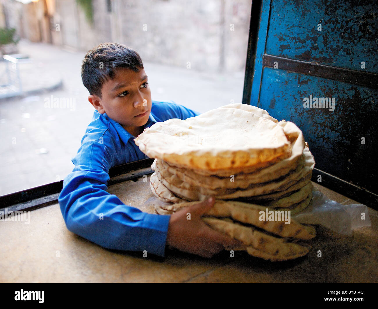 Syrian schoolboy collecting fresh bread from local bakery early in the ...