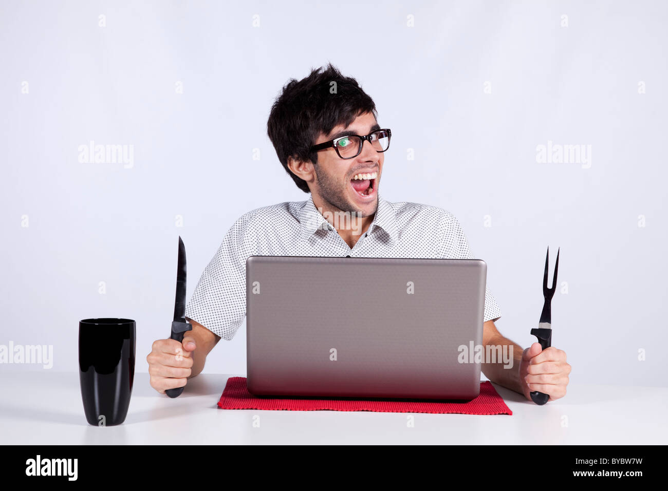Young men at dinner table eating technology with a funny face ...