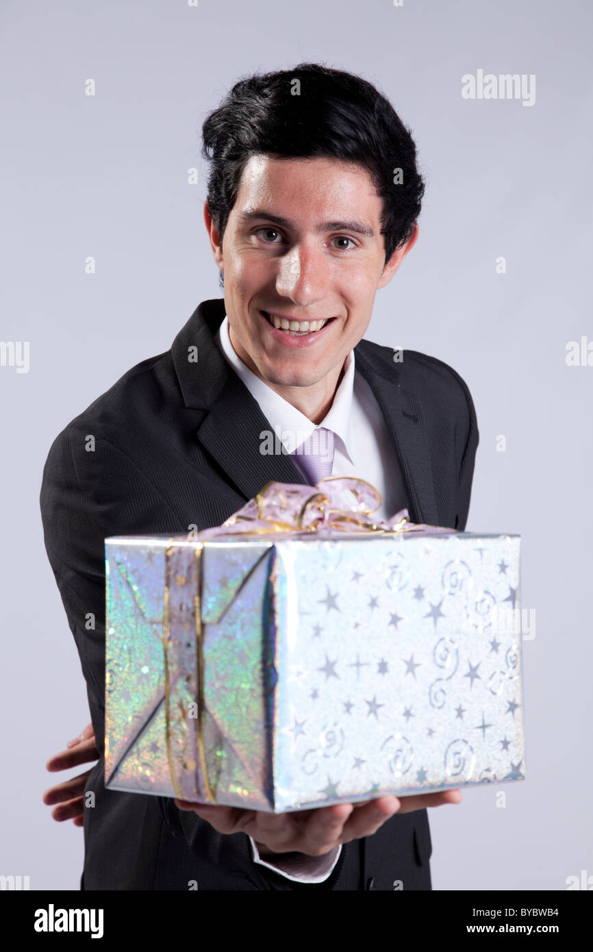 Businessman offering you a gift (isolated on gray Stock Photo - Alamy