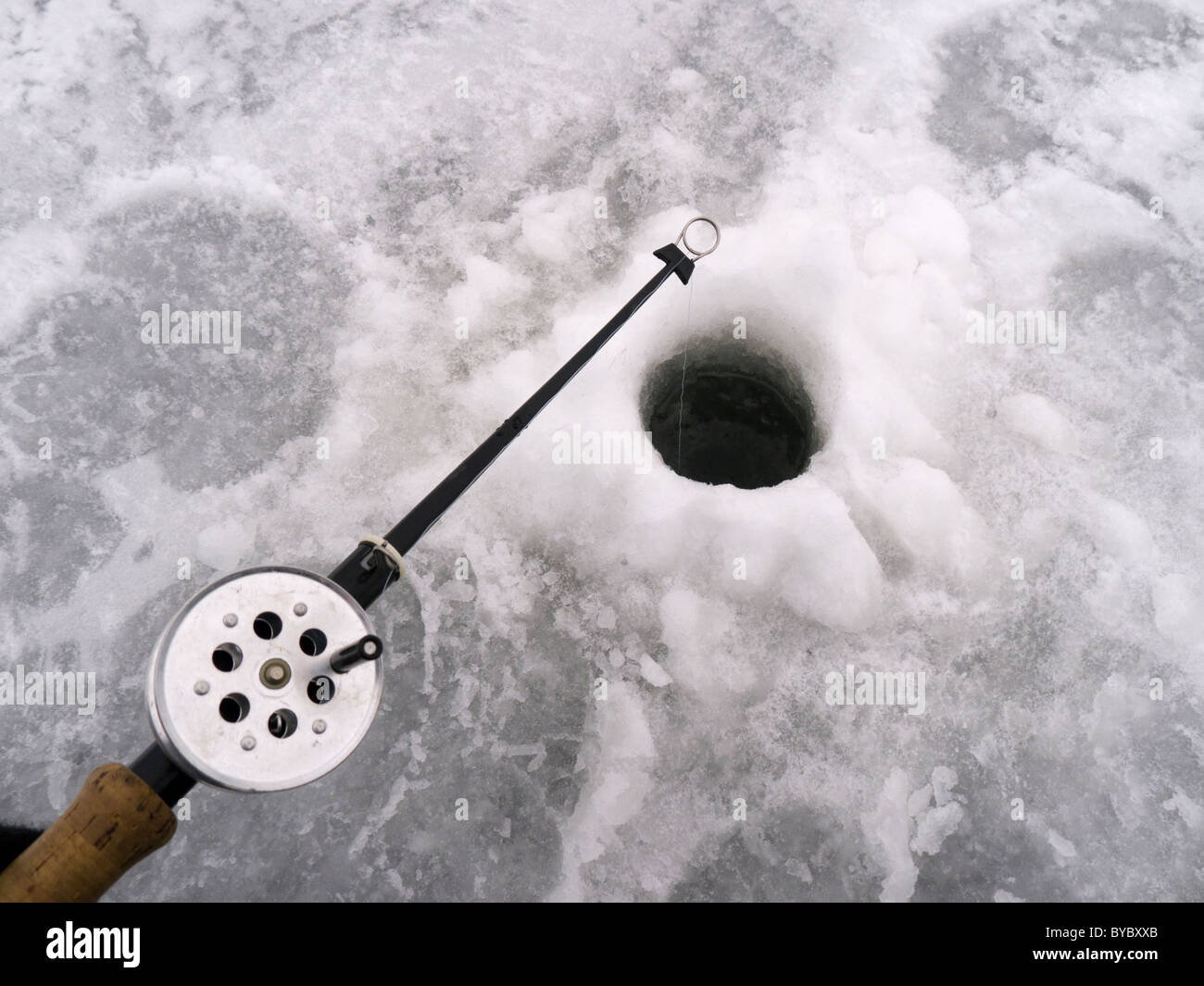 Close-up on ice fishing rod held over a hole in the ice Stock Photo - Alamy