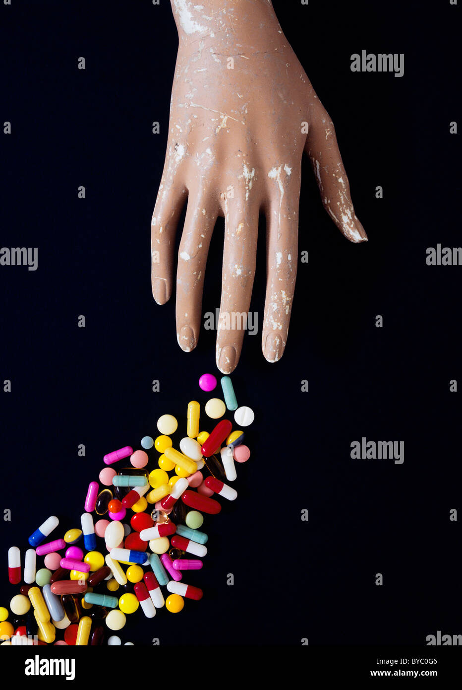 Damaged dummy hand grabing an assortment of medical capsules, pills and ...