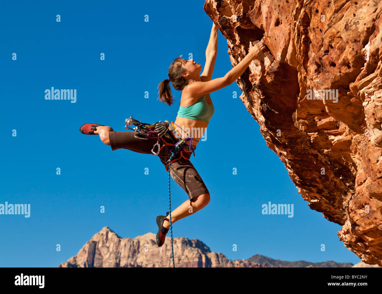 Female rock climber struggles for her next grip dangling on the edge of ...