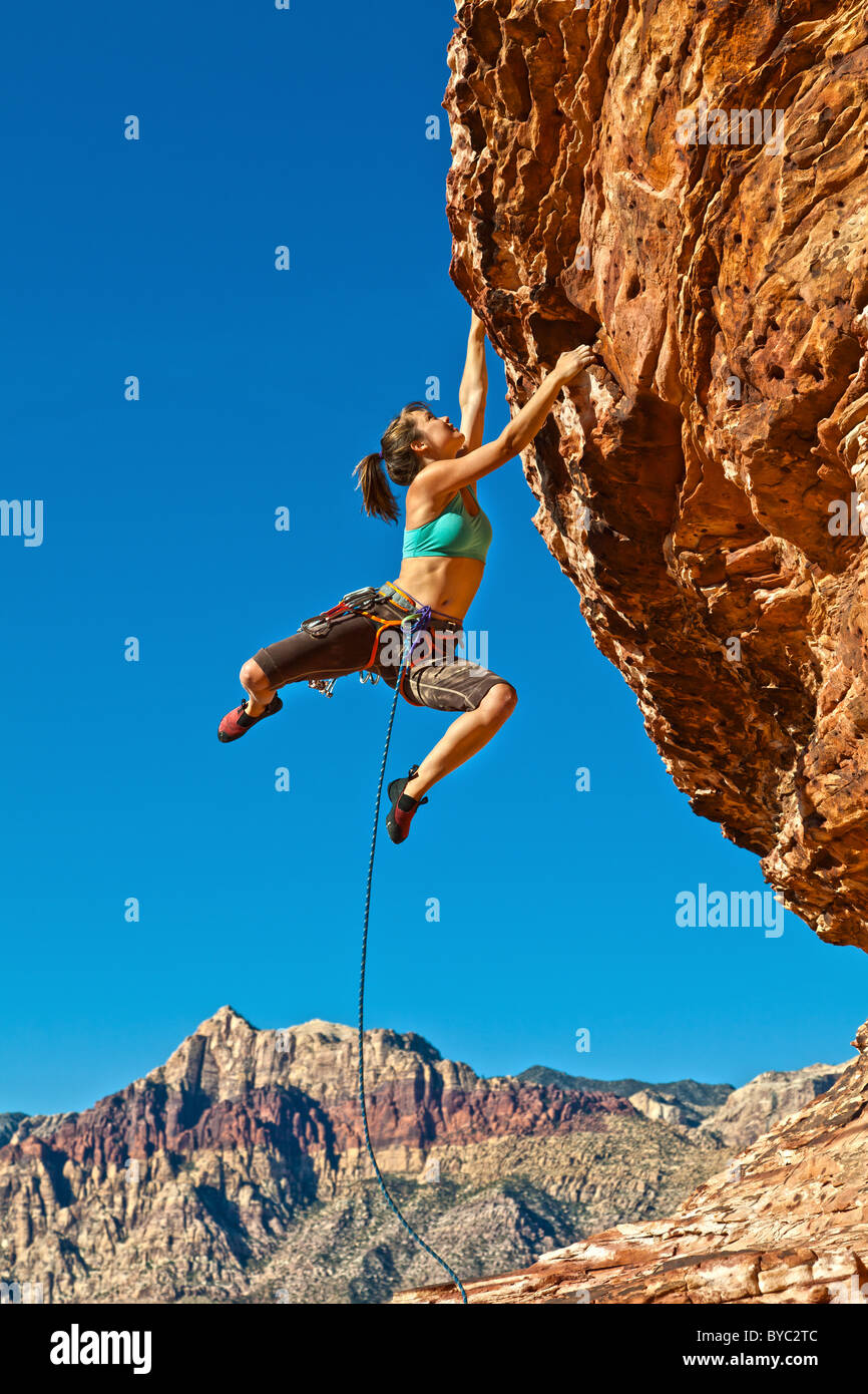 Female rock climber struggles for her next grip dangling on the edge of ...