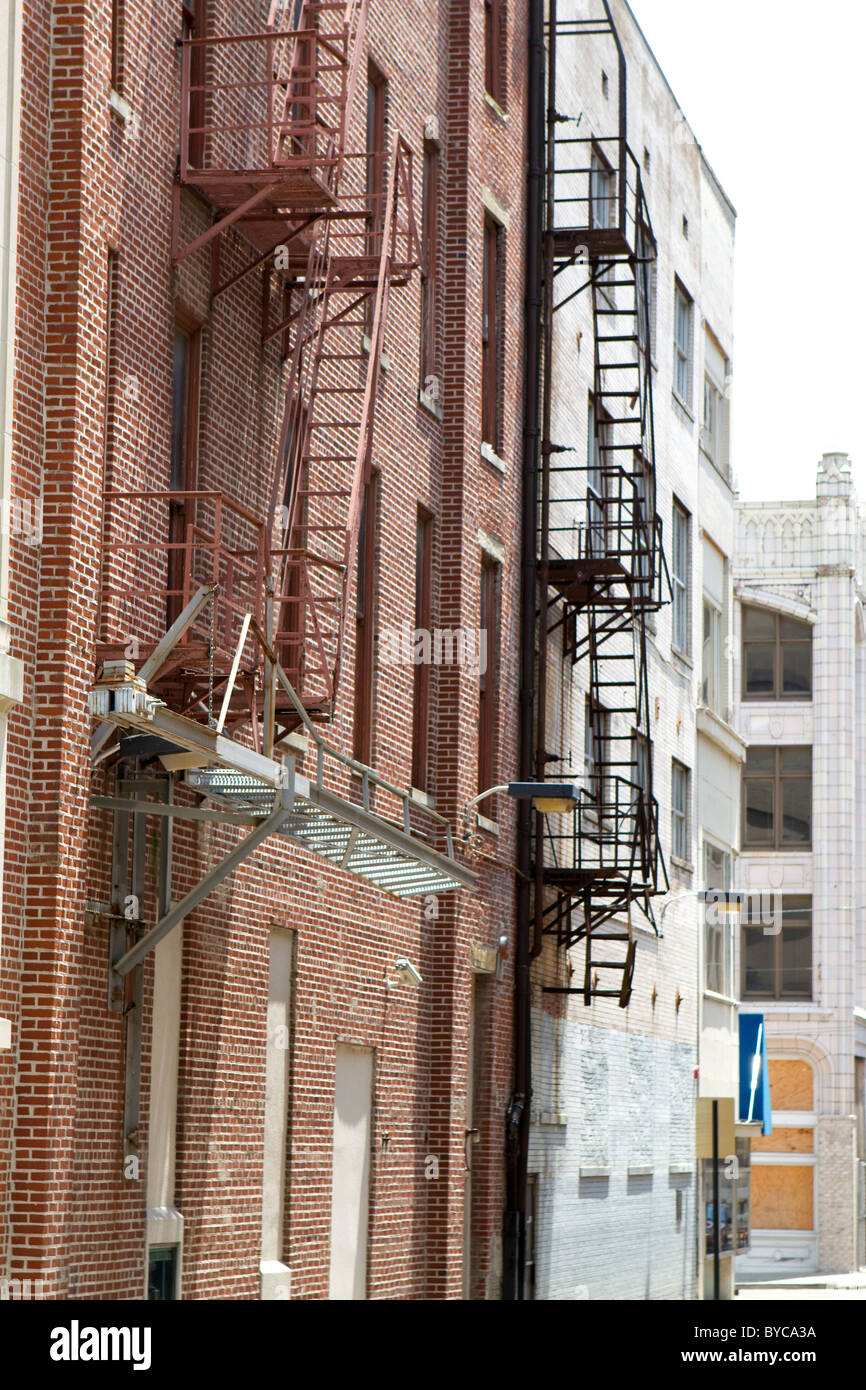 Old fire escapes are attached to the exterior of brick buildings in ...