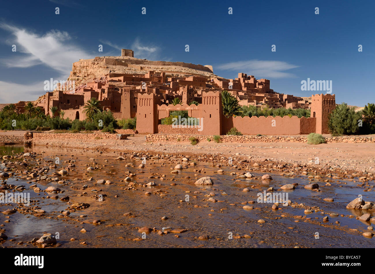 Ancient red city of Ait Benhaddou with shallow water of Ounila River or ...