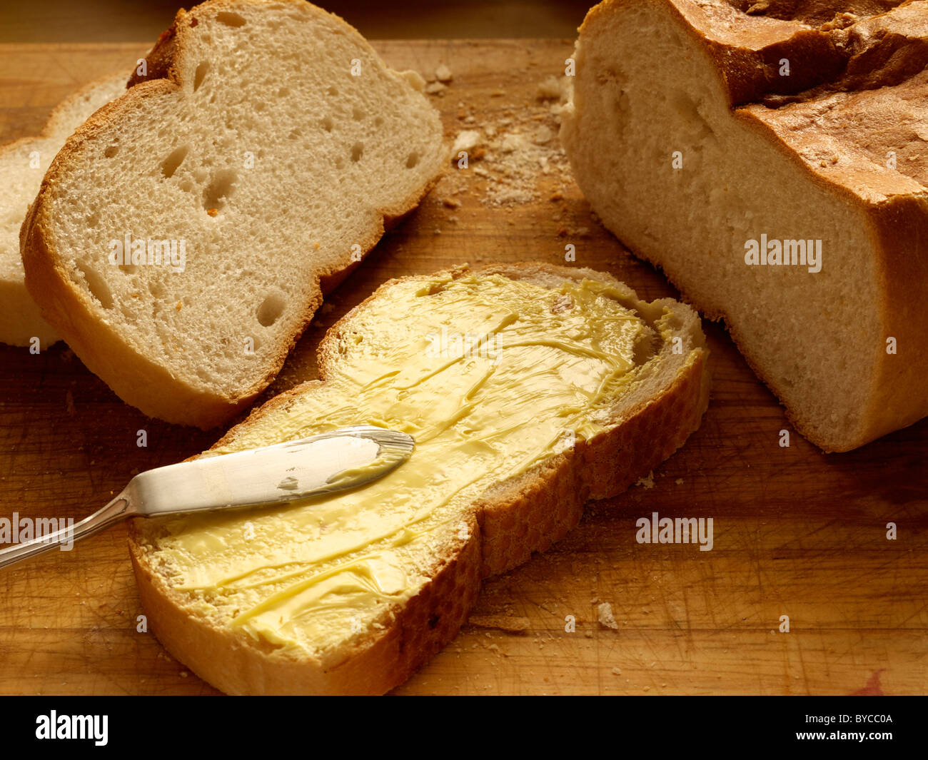 Sliced White bread and half a unsliced loaf and a butter knife on top ...