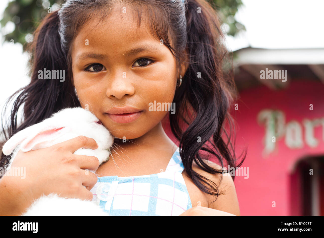 Young girl cuddling bunny rabbit with pink building in background Stock ...