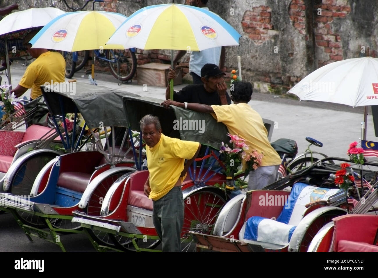 Colorful cyclos with umbrellas are lined up as drivers are working at a ...