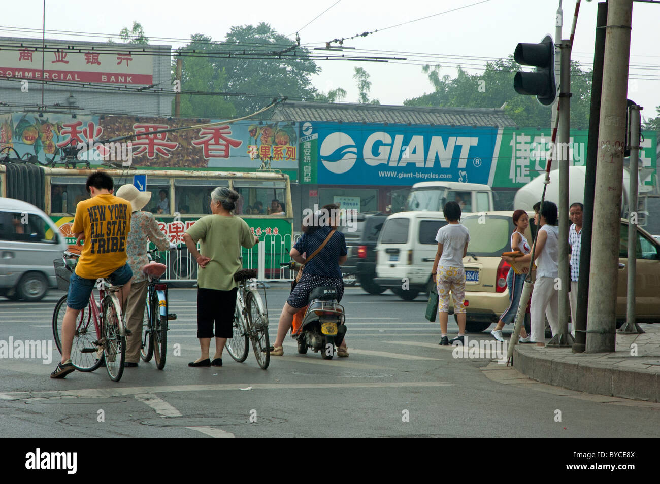 People on bicycles stopped at a red traffic light, Hutong district ...