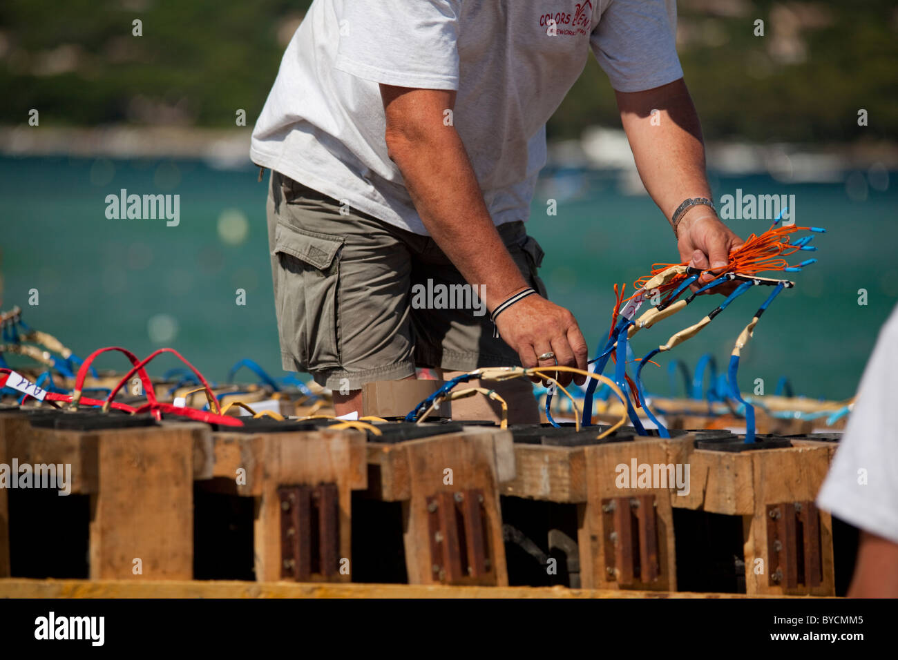 Man installing firework rockets on a floating raft and holding fuses in ...