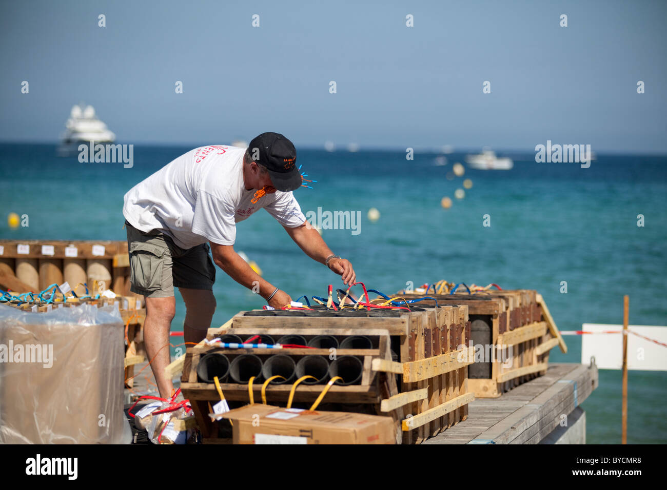 Man installing firework bombs on a floating raft and holding fuses in ...