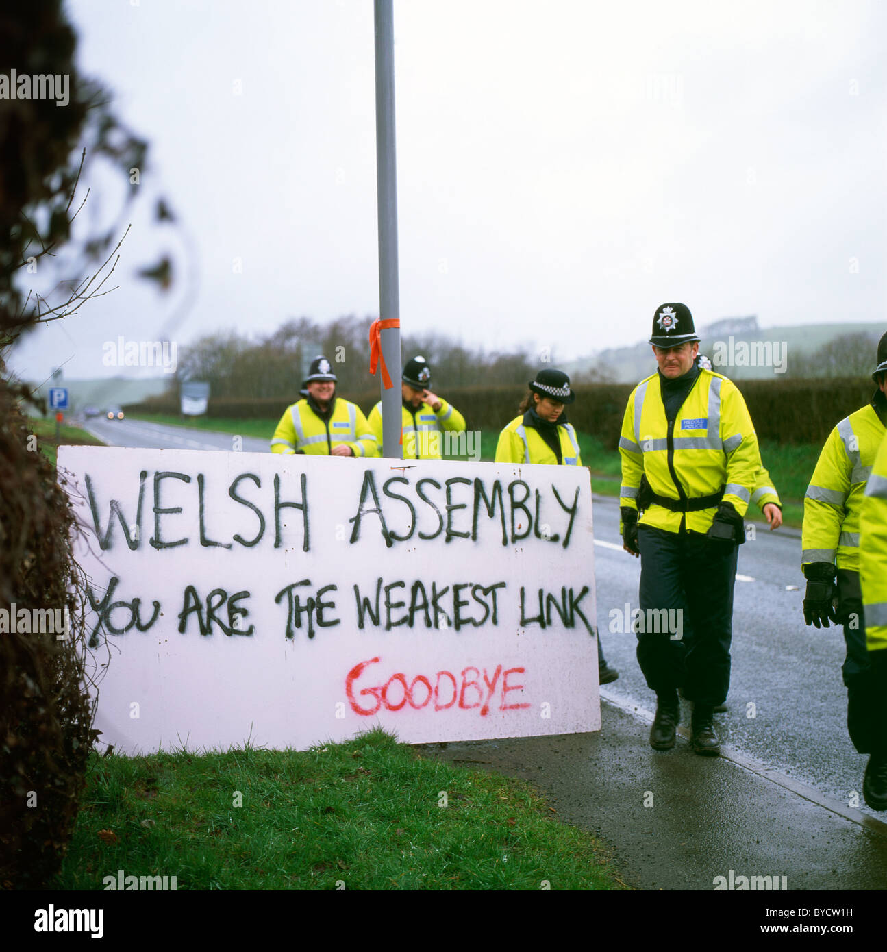 Welsh police walking past a sign criticizing the Welsh Assembly during ...
