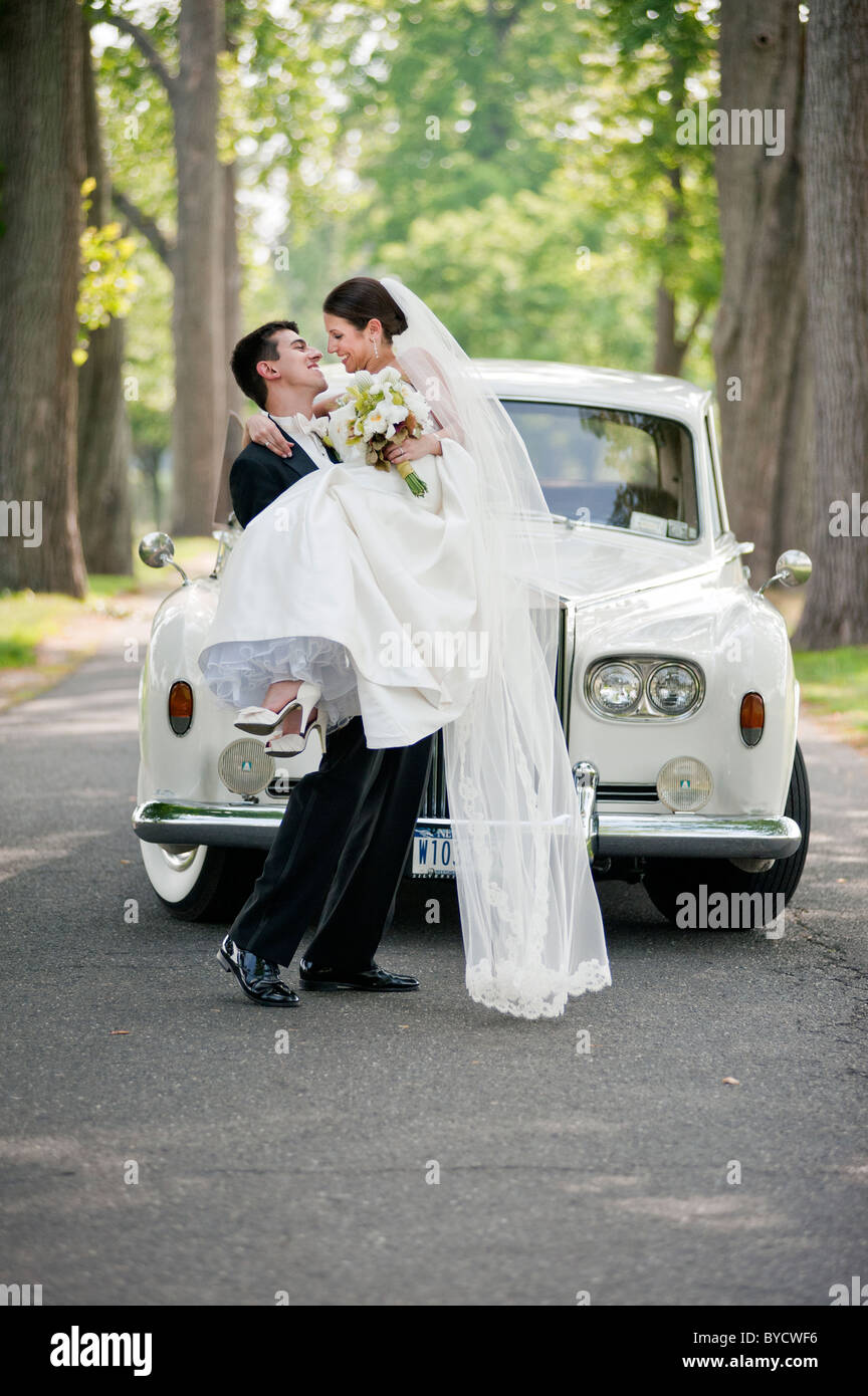 Newly married groom holding his new bride in his arms as they arrive at ...