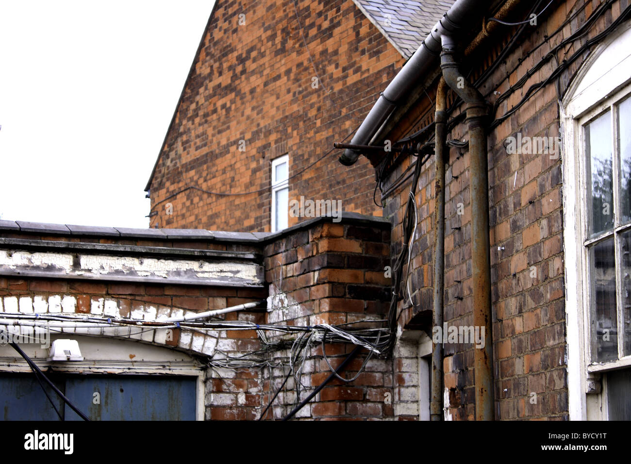 A wiring disaster on the outside of a building next to the downpipe and ...