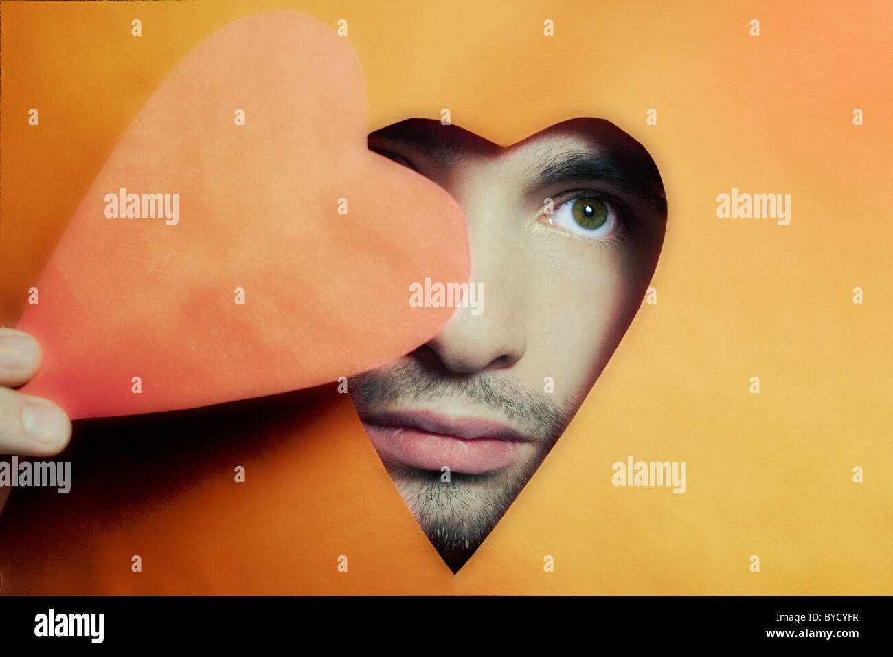 Face of young man peering from hole in heart-shaped closeup Stock Photo ...