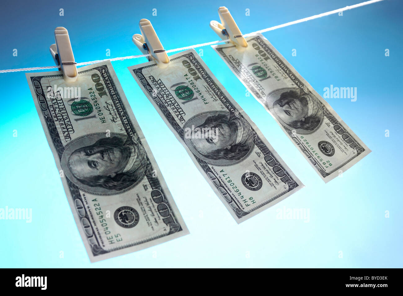 Hundred dollar bills drying on a clothes line isolated on blue sky ...
