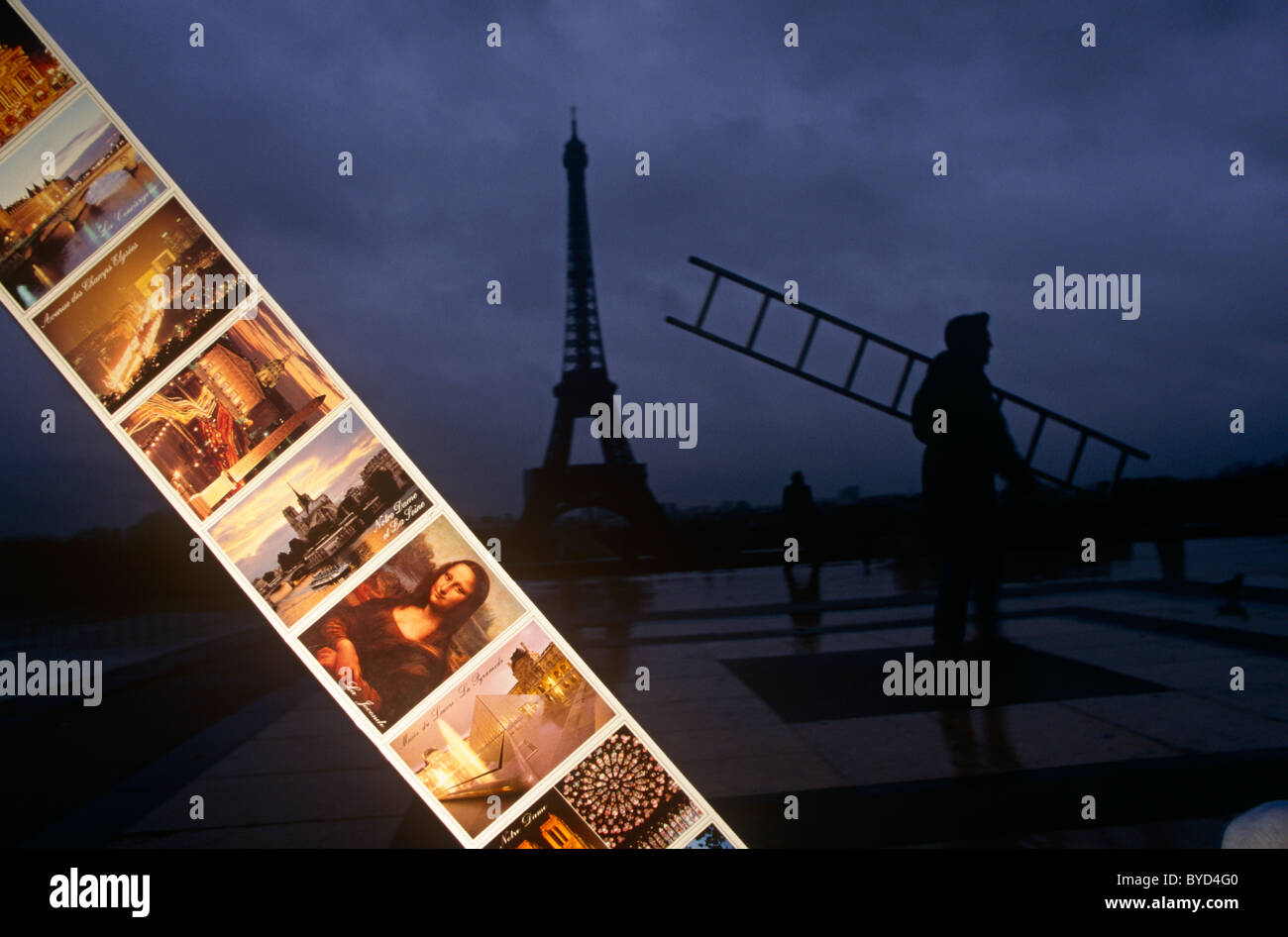 Strip of tourist postcards on sale as a workman passes-by carrying ...