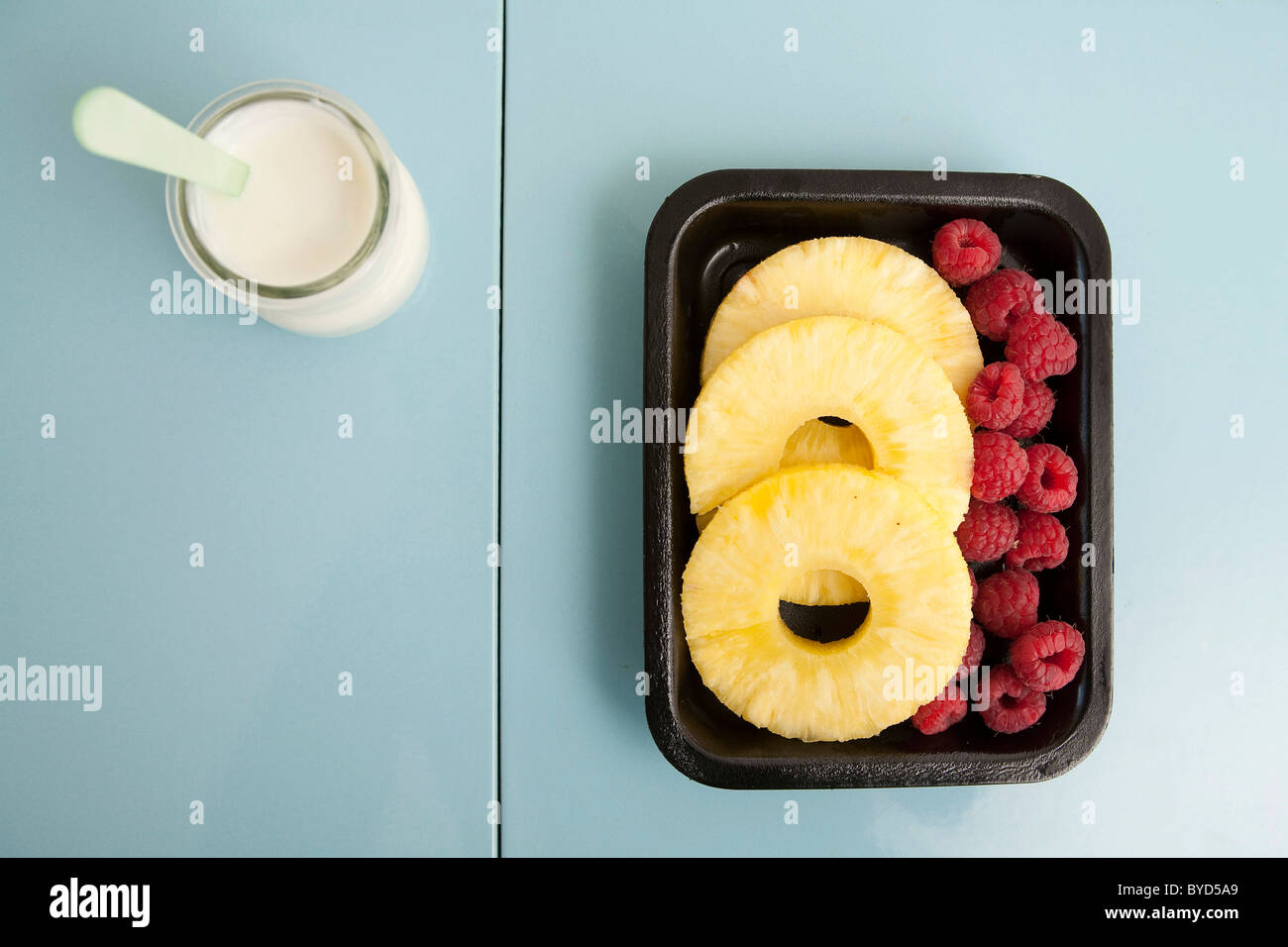 Packaged pineapple slices and raspberries with a tub of yoghurt Stock ...