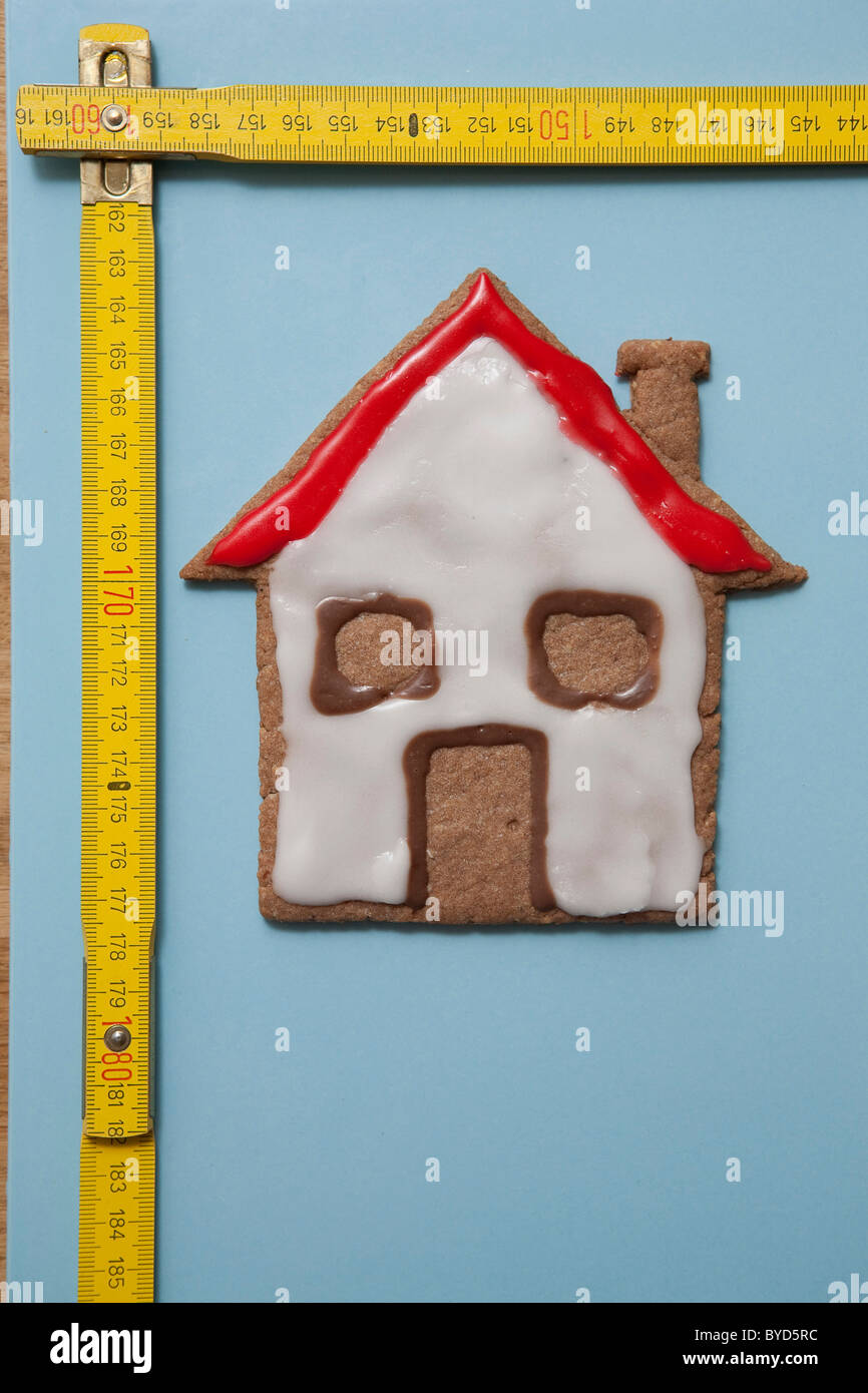 House biscuit with a measuring stick, symbolic image for home ...