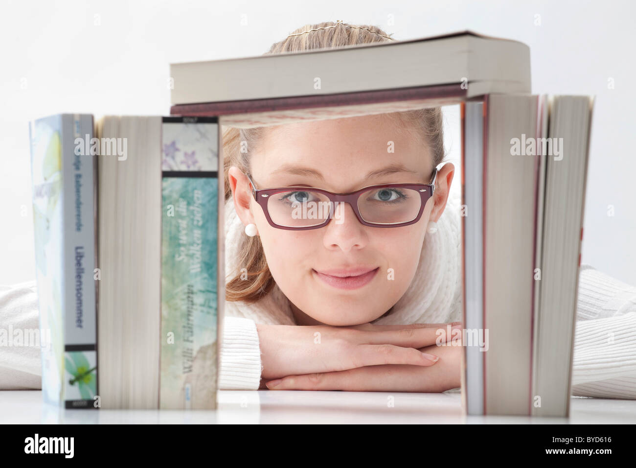 Young woman with glasses looking through a stack of books Stock Photo ...
