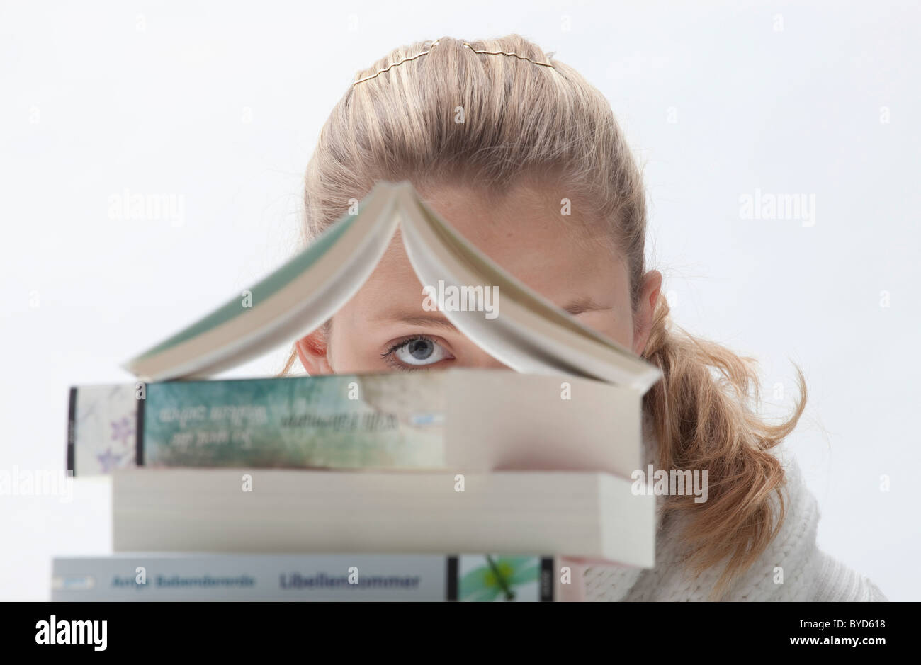 Young woman with glasses looking through a stack of books Stock Photo ...