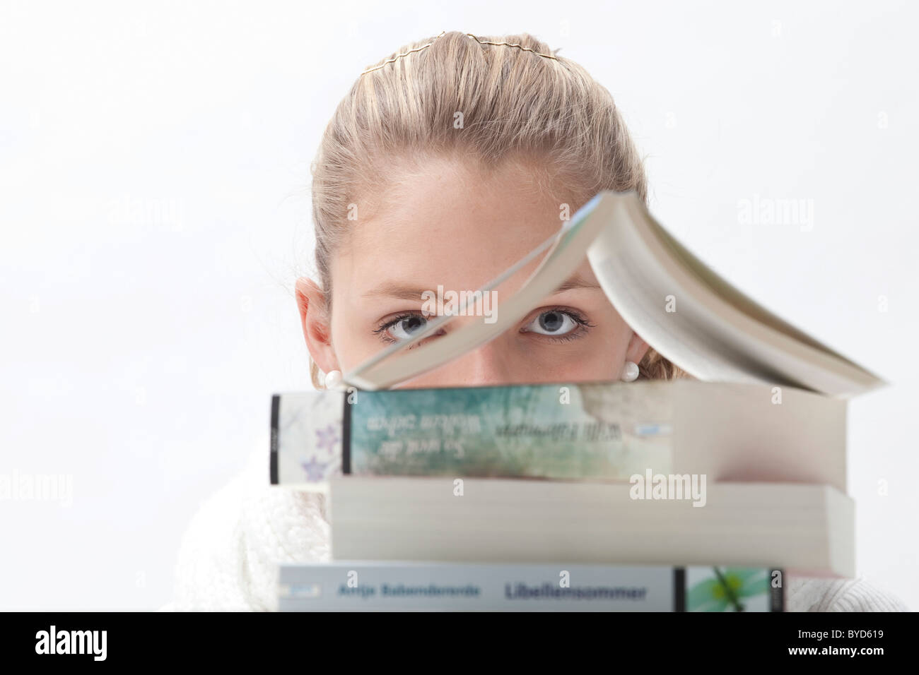 Young woman with glasses looking through a stack of books Stock Photo ...