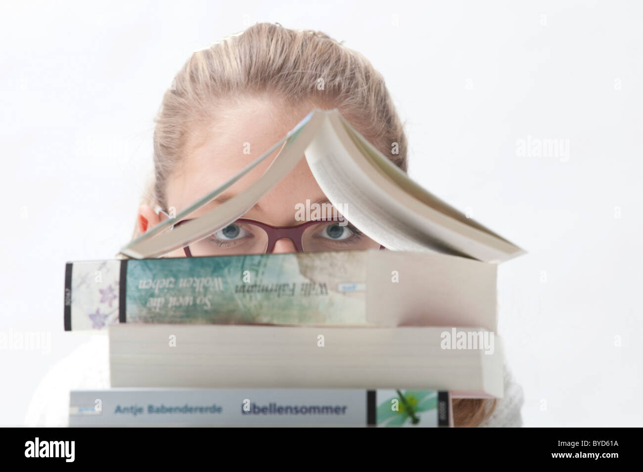 Young woman with glasses looking through a stack of books Stock Photo ...