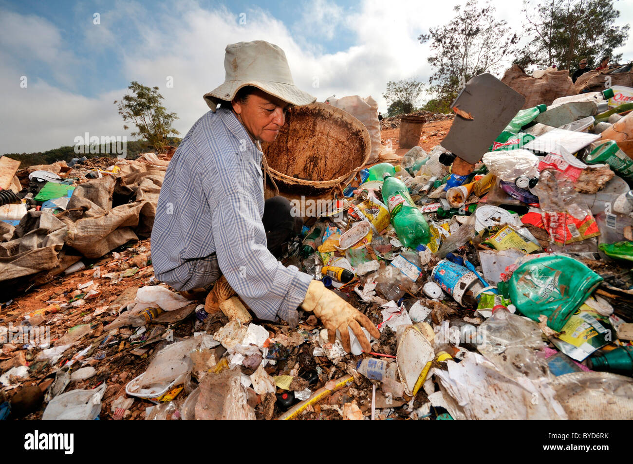 Garbage collector pre-sorting different coloured plastic recyclables ...