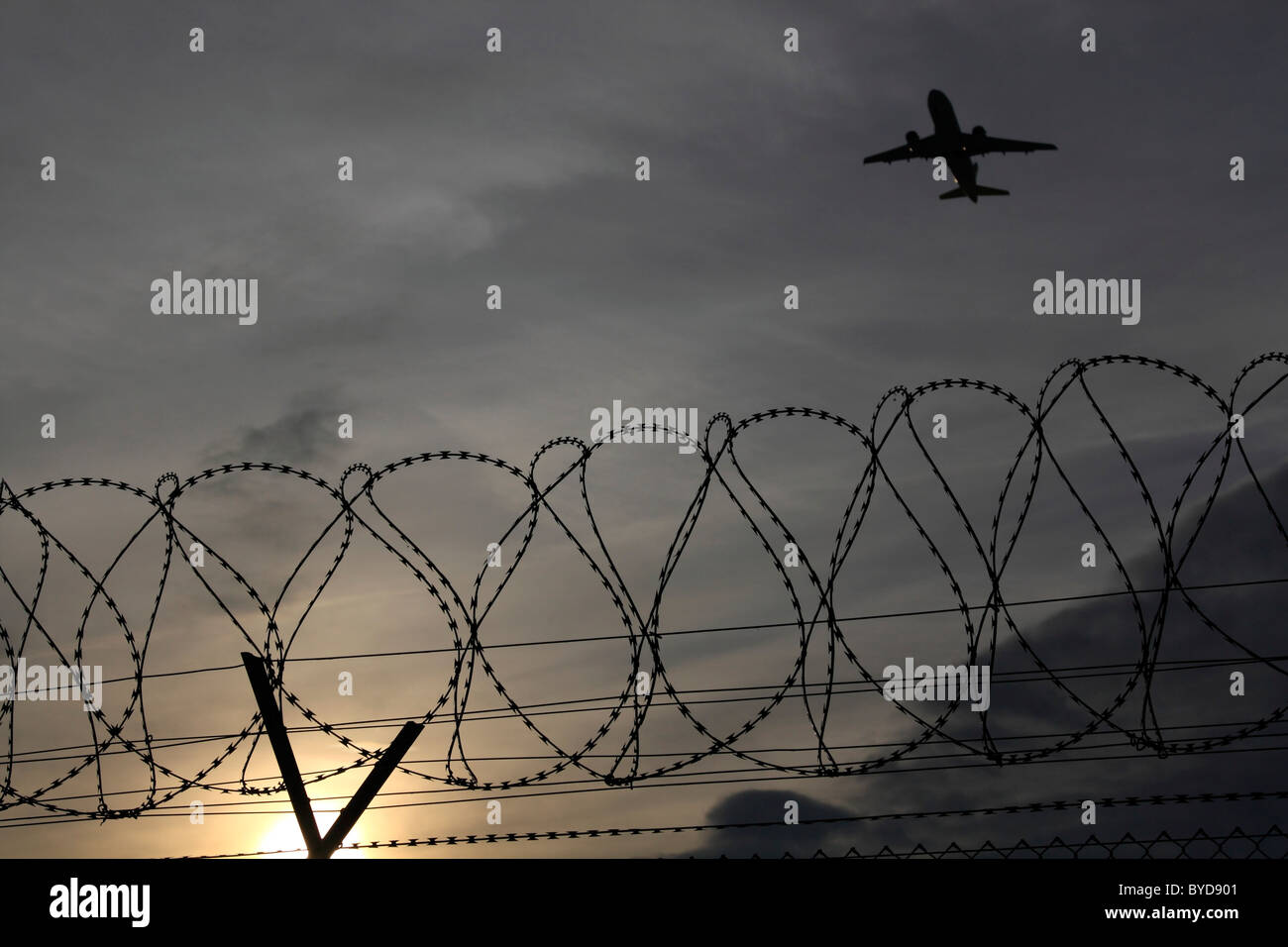 Security fence with an aircraft flying overhead, Stuttgart Airport ...